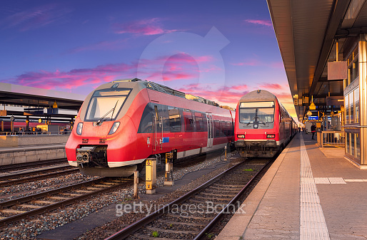 Beautiful red commuter trains on railway station and colorful sky at ...