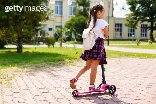 Child riding scooter on way back to school. Little girl playing ...