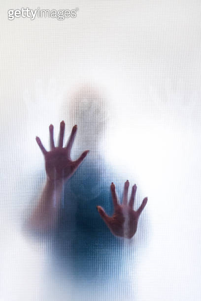 Spooky silhouette of woman with hands pressed against glass window 이미지 ...