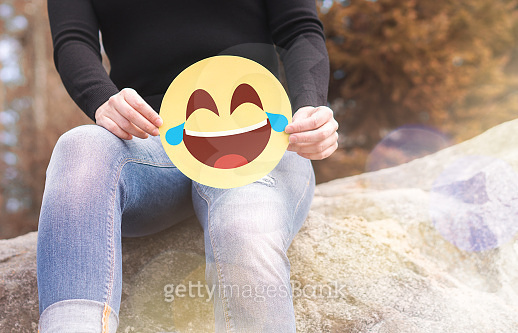 Laughing emoticon with tears of joy. Woman having fun outside and ...