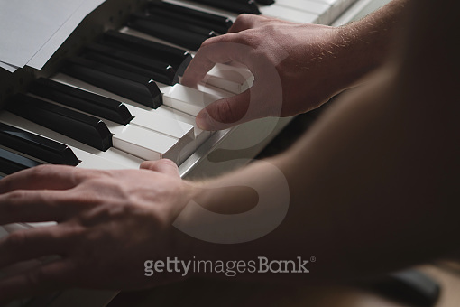 Close up of man playing piano. Intimate view of hands on keyboard keys ...