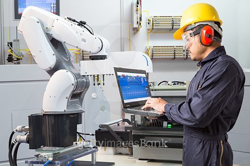 Engineer using laptop computer for maintenance automatic robotic hand machine tool in smart ...