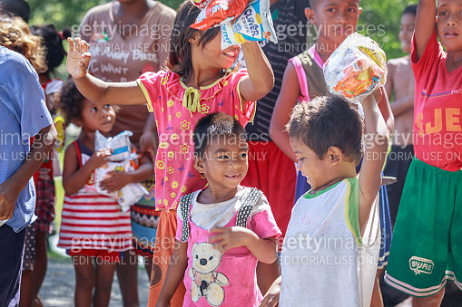 Filipino children standing in a line and holding snack in their hands ...