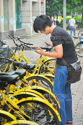 People use smartphone to scan the QR code on a shared bike to unlock it ...