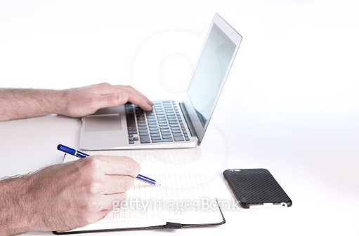 hands of a male person taking notes while working on a laptop computer ...