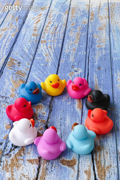 Group of multi-colored rubber ducks sit together in a circle on an old ...