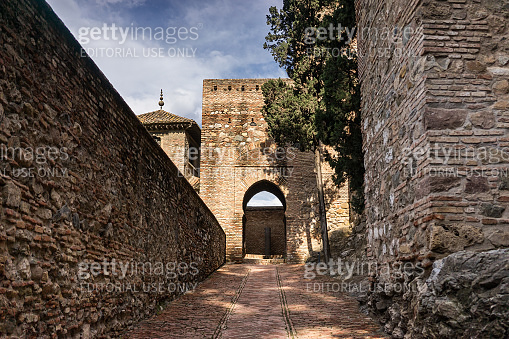 Medieval stone arches and walkway by the walls and towers of an ancient ...