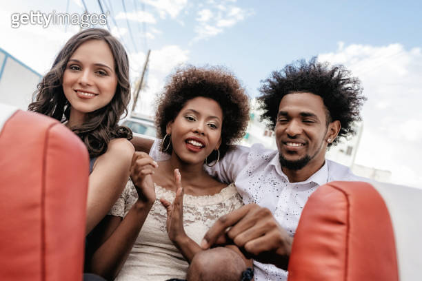 three happy young cuban friends singing in cabrio in Havanna streets ...