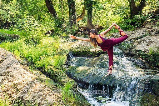 Pretty young woman practicing yoga in nature: posture of the dancer ...
