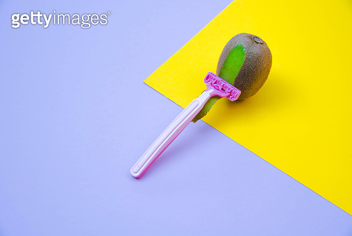 Kiwi fruit and razor on violet and yellow background. Hair removal ...