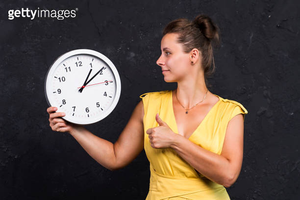 A young woman is holding a watch. Time concept. A girl with a clock in ...