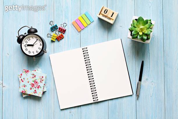 Desk table with open notebook paper, cube calendar and clock ...