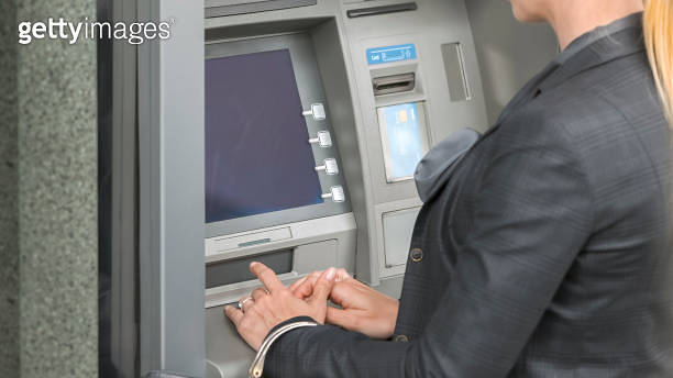Female hands shielding keypad while entering PIN number on ATM ...