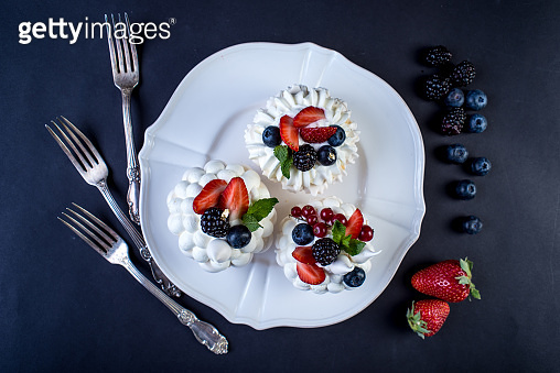 Delicate white meringues with fresh berries on the plate. Dessert ...