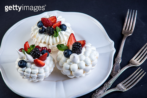 Delicate white meringues with fresh berries on the plate. Dessert ...