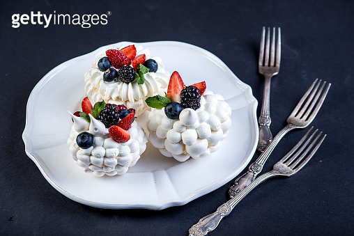 Delicate white meringues with fresh berries on the plate. Dessert ...