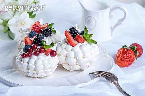 Delicate white meringues with fresh berries on the plate. Dessert ...