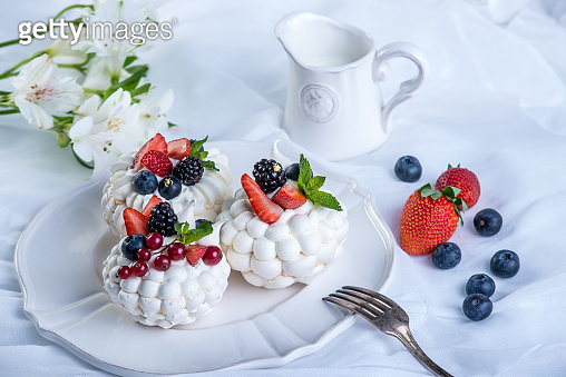 Delicate white meringues with fresh berries on the plate. Dessert ...