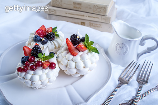 Delicate white meringues with fresh berries on the plate. Dessert ...