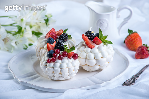 Delicate white meringues with fresh berries on the plate. Dessert ...