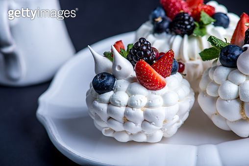 Delicate white meringues with fresh berries on the plate. Dessert ...