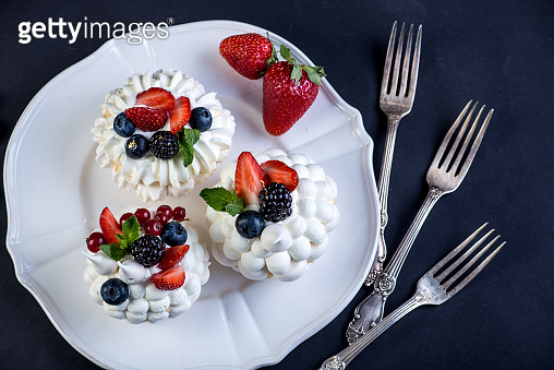 Delicate white meringues with fresh berries on the plate. Dessert ...