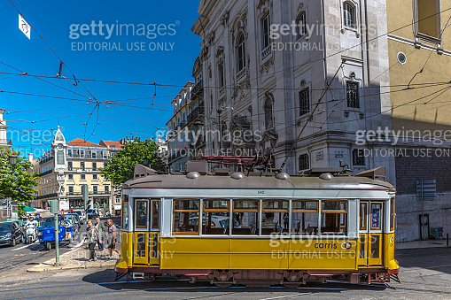 Tourist and locals riding a traditional yellow tram in downtown Lisbon ...