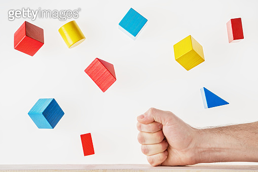 The fist strikes the table and the multicolored wooden geometric shapes ...