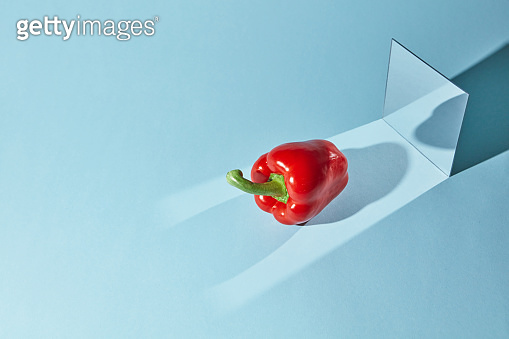 Red pepper, a square mirror on a blue background, a reflection of an ...