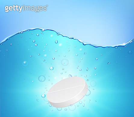 Effervescent soluble tablet falling down under the water with bubbles ...