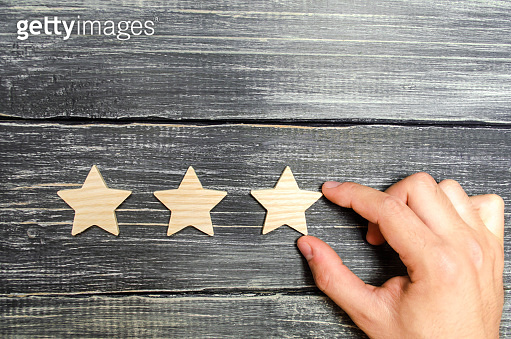 The hand puts the third star. concept of success and recognition ...