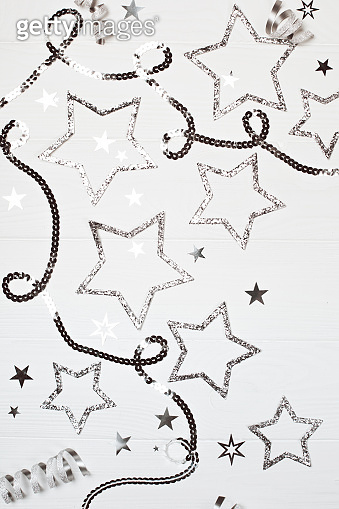 Silver sparkling stars with sequin chain on white wooden background ...
