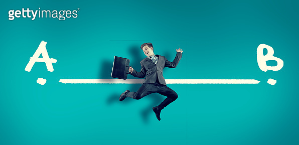 Business man on a simple background jumping in front of line between ...