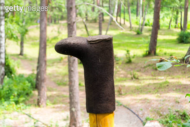 The old black felt boots stretched over a log stuck into the ground ...