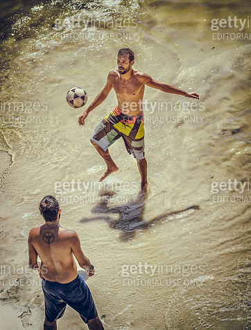 Two young brazilian men playing soccer on Copacabana Beach on a hot ...