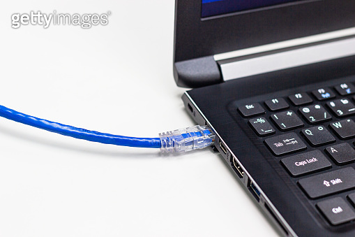 Closeup blue cable network connection to a Lan port of a laptop on ...