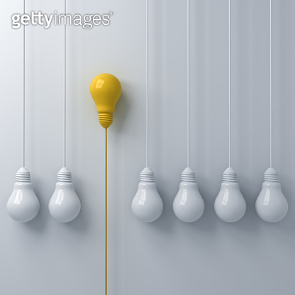 Think different concept One hanging yellow light bulb standing out from ...