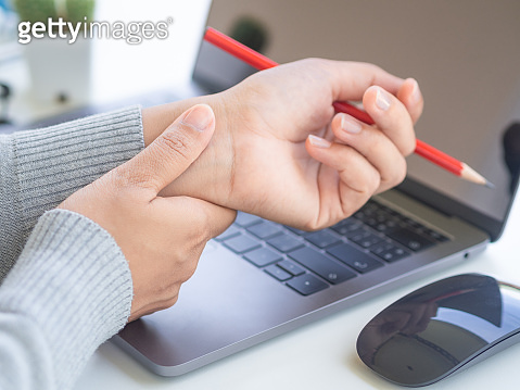 Closeup woman holding her wrist pain from using computer long time ...