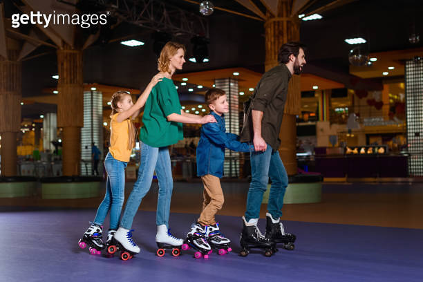 parents and kids skating together on roller rink (1007094296) - 게티이미지뱅크
