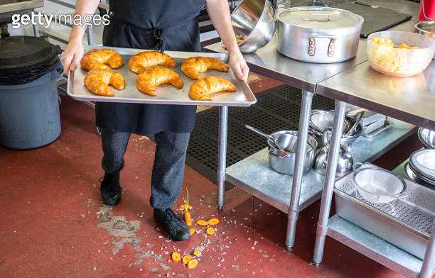 A chef carry a baking tray in a messy kitchen with the risk of slipping ...