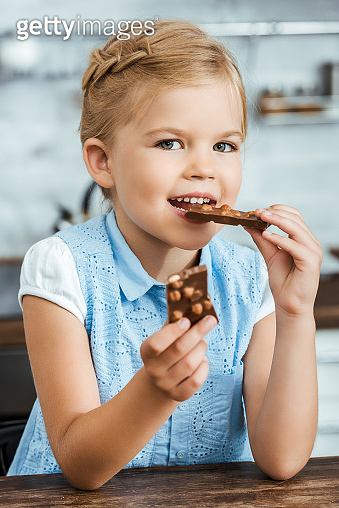 cute happy kid eating delicious chocolate with hazelnuts and smiling at ...
