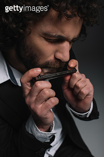 close-up portrait of expressive young man playing harmonica on black ...