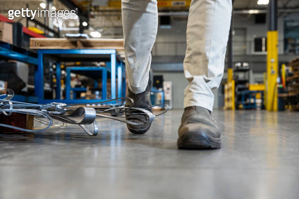 An industrial safety topic. A worker tripping over a poorly placed ...
