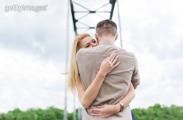 Young man is hugging with his loving girl on the bridge. Back view ...