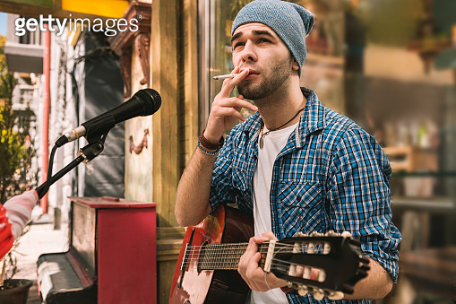 Pensive male guitarist smoldering cigarette on street (1055029002) - 게티 ...