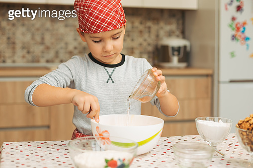 Boy pouring water in a bowl while mixing ingredients to cook 이미지 ...