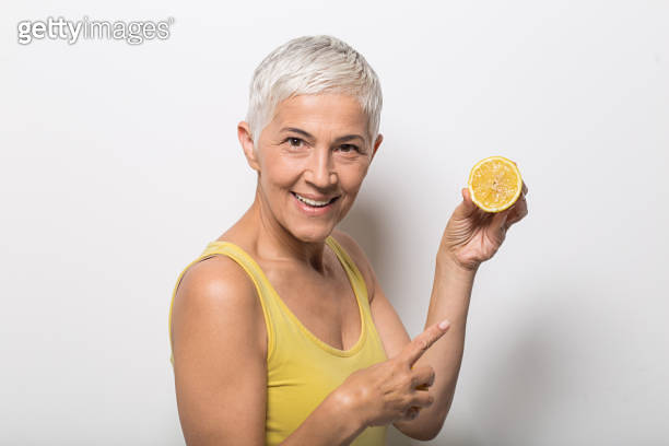 Mature woman holding lemon and pointing finger at it 이미지 (1012098238 ...