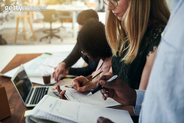 Focused work colleagues comparing notes together in an office 이미지 ...