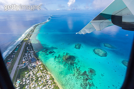Tuvalu under the wing of an airplane, aerial view of airport. Vaiaku ...