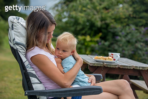 Young mother, holding her cute baby boy outdoor, cuddle him, kissing ...